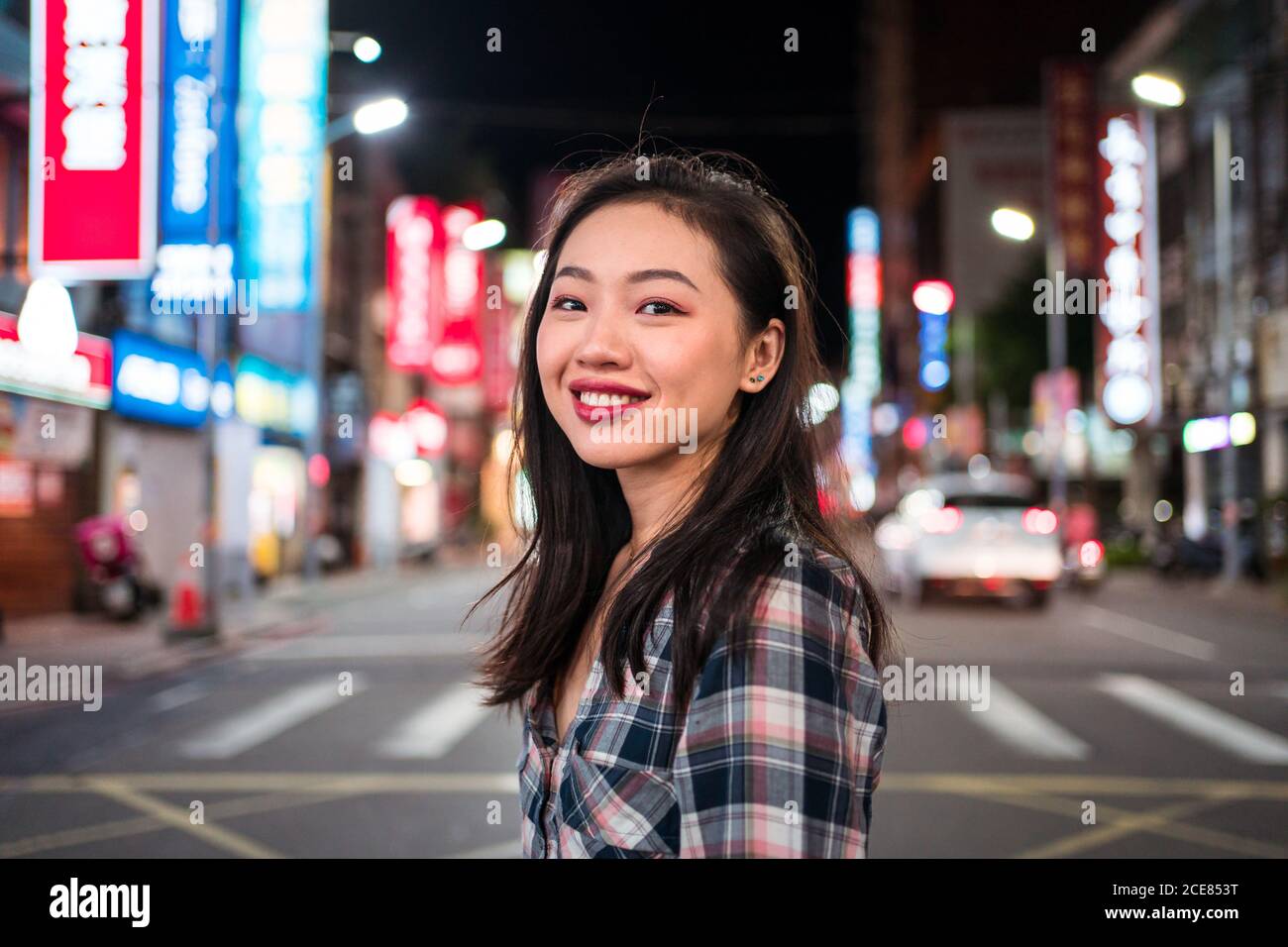 Side view of cheerful millennial Asian female in checkered shirt ...