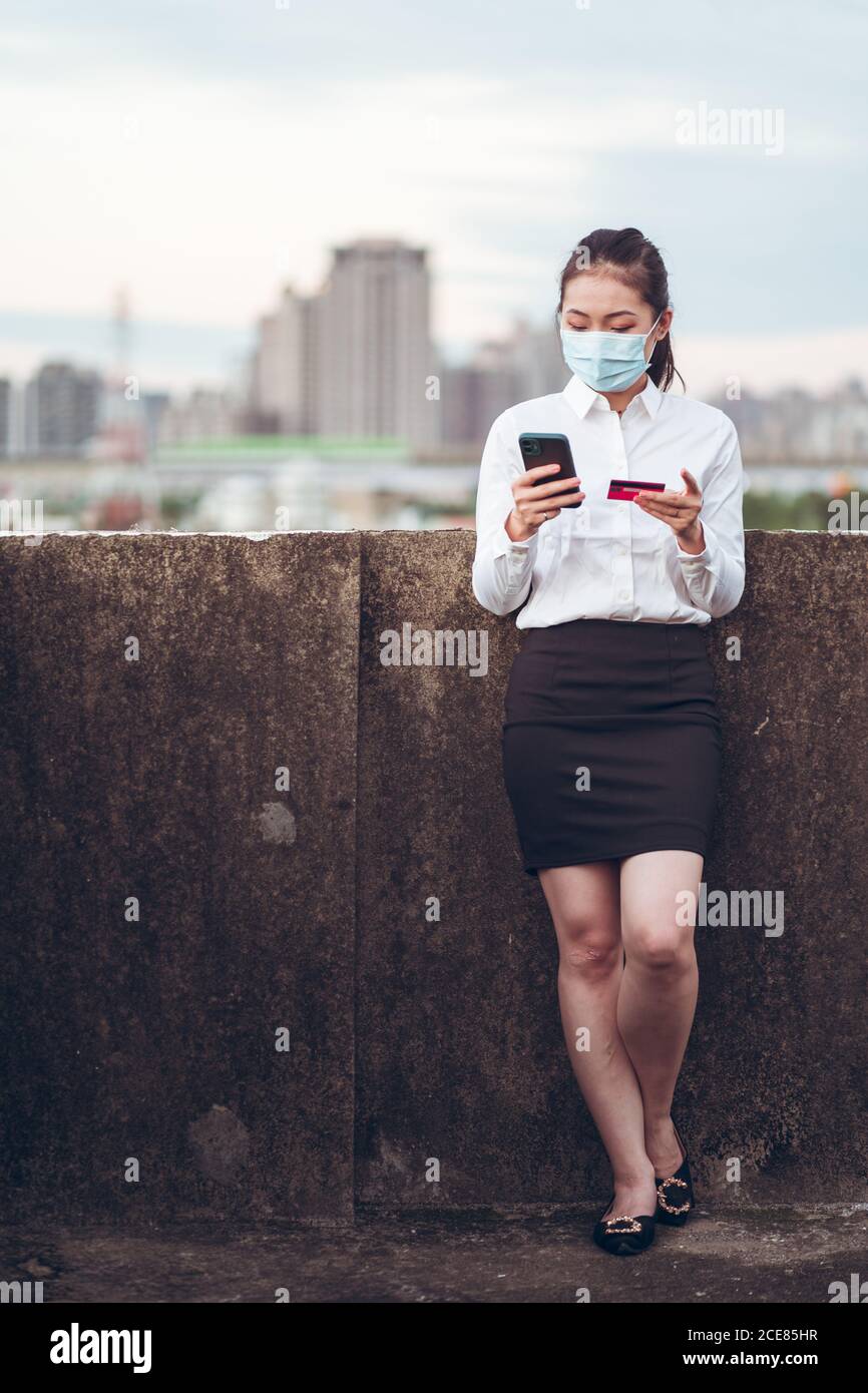 Young Asian female remote employee in formal clothes and medical mask ...