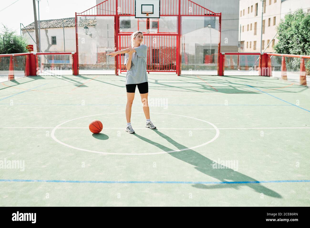Full body side view of female basketball player stretching shoulders ...