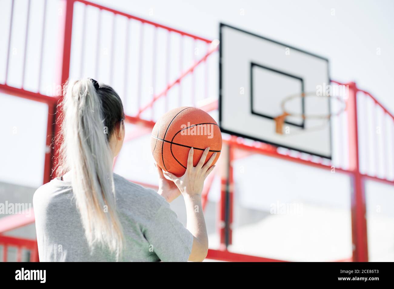 Back view of young sporty Woman performing shot while playing ...