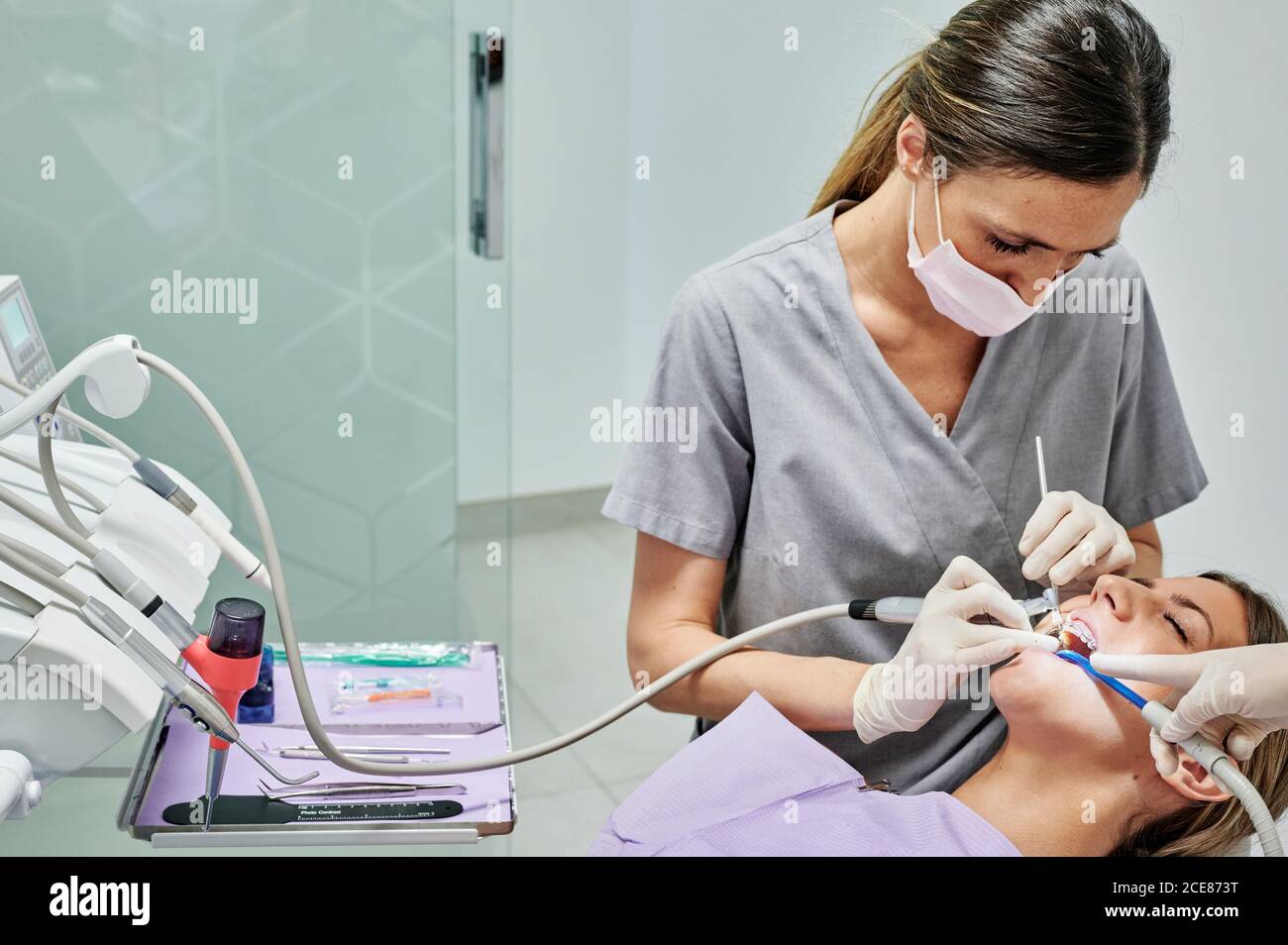 Dental doctor checking teeth of female client wearing braces while ...