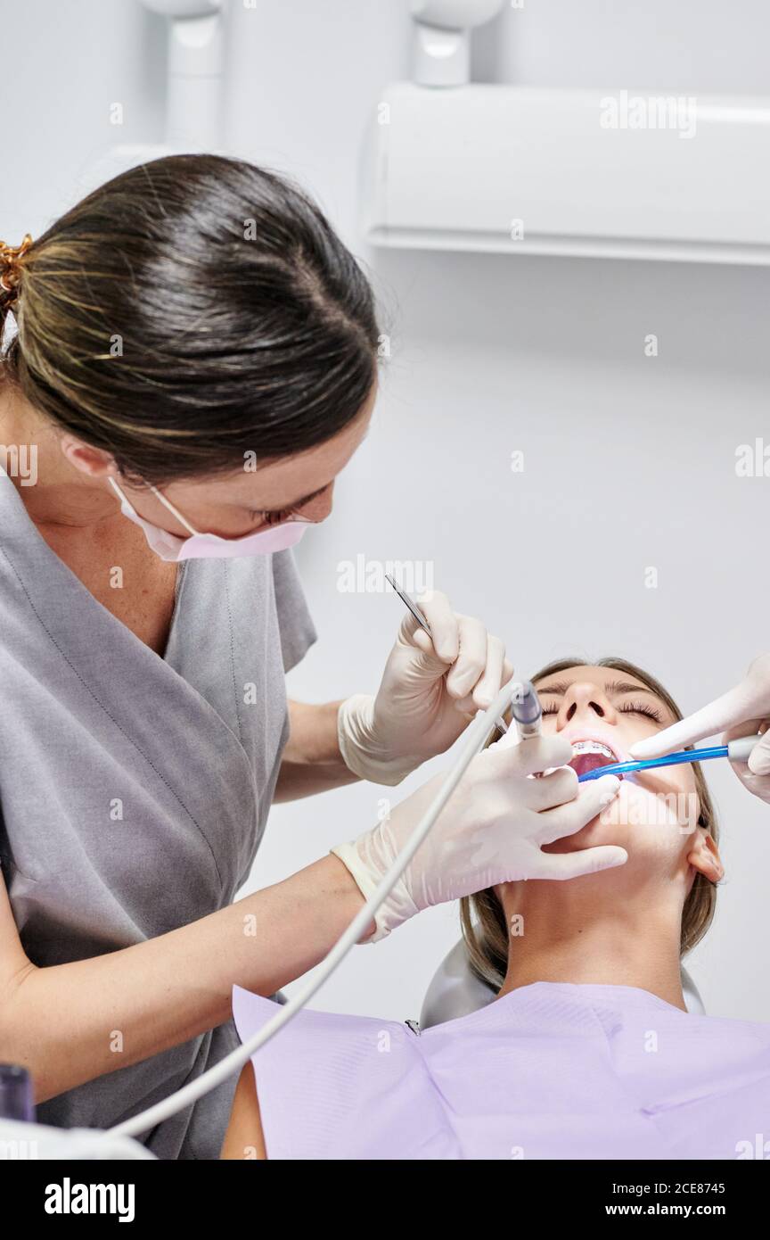 Dental doctor checking teeth of female client wearing braces while ...