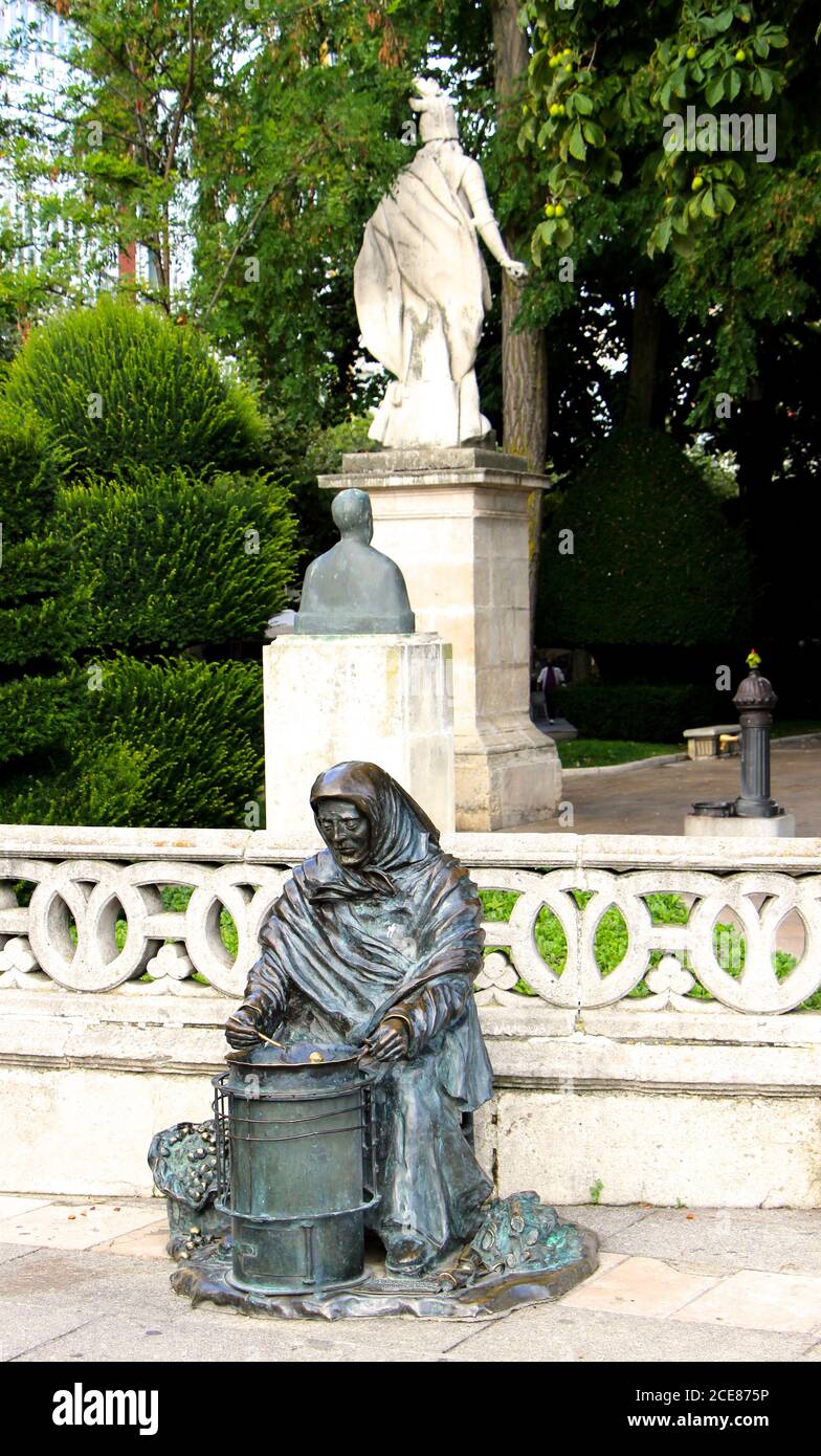 Bronze statue of seated old woman selling roasted chestnuts a stone ...