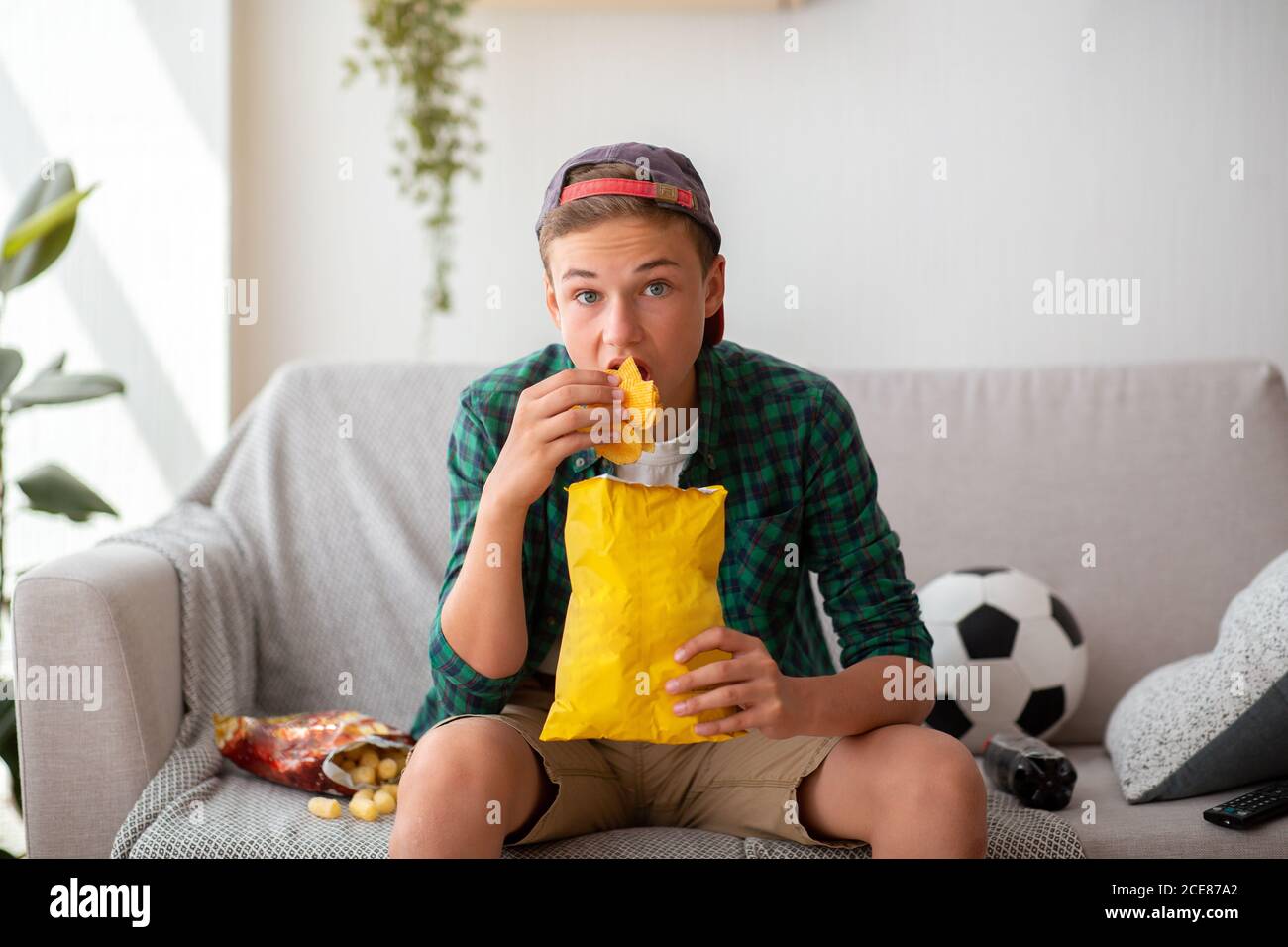 Boy watching tv eating chips hi-res stock photography and images - Alamy