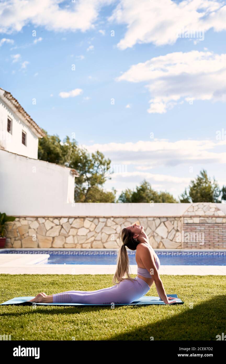 Side view of peaceful female practicing yoga on mat in Bhujangasana ...
