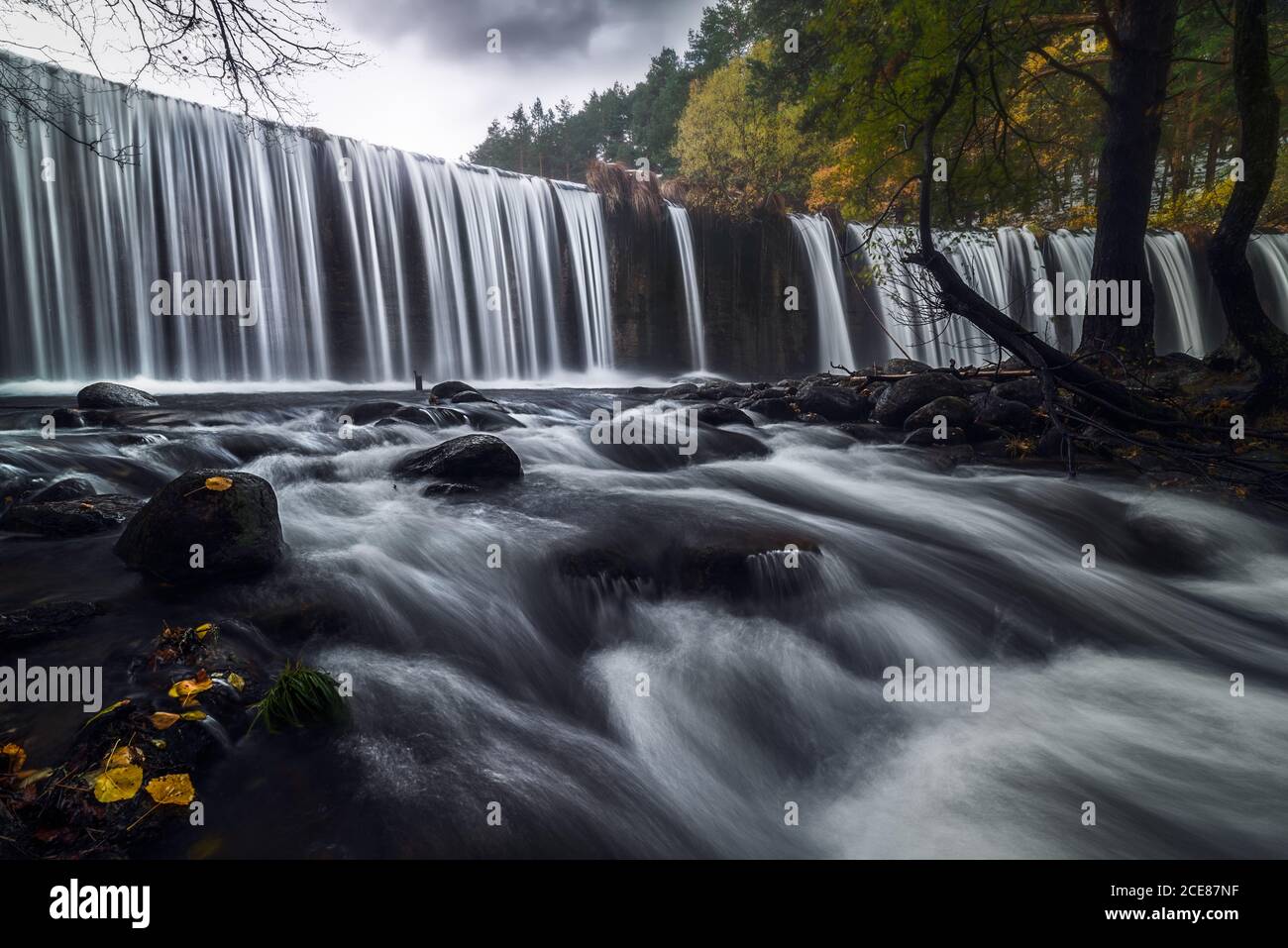 Picturesque scenery of rapid river with wide waterfall and rocky bottom ...