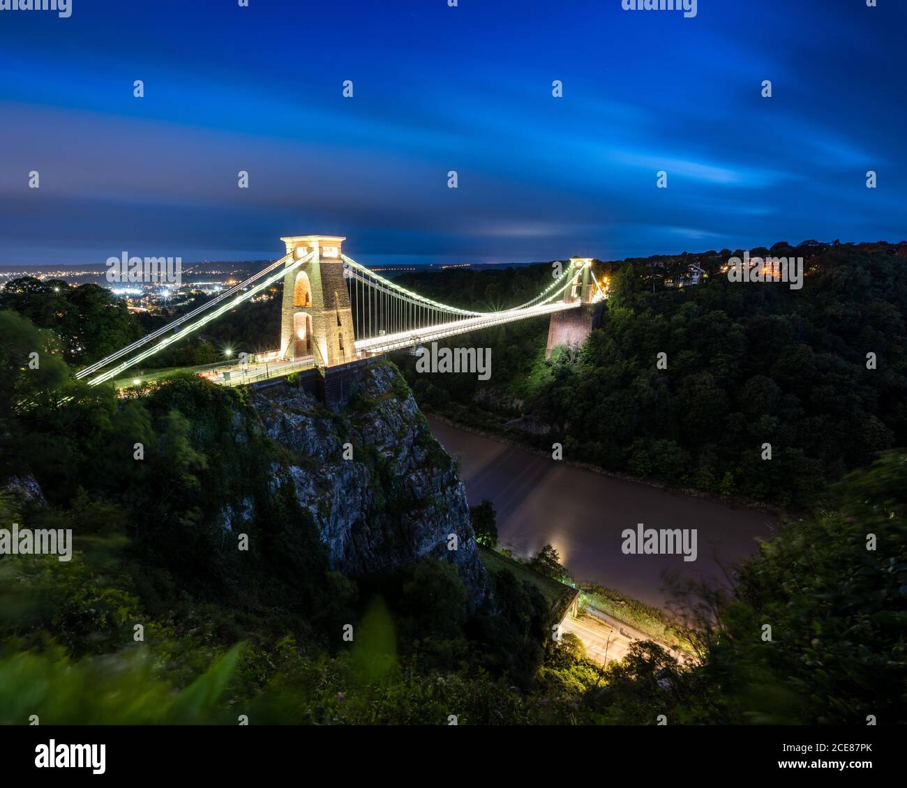 The iconic Clifton Suspension Bridge is lit at dusk over the River Avon ...
