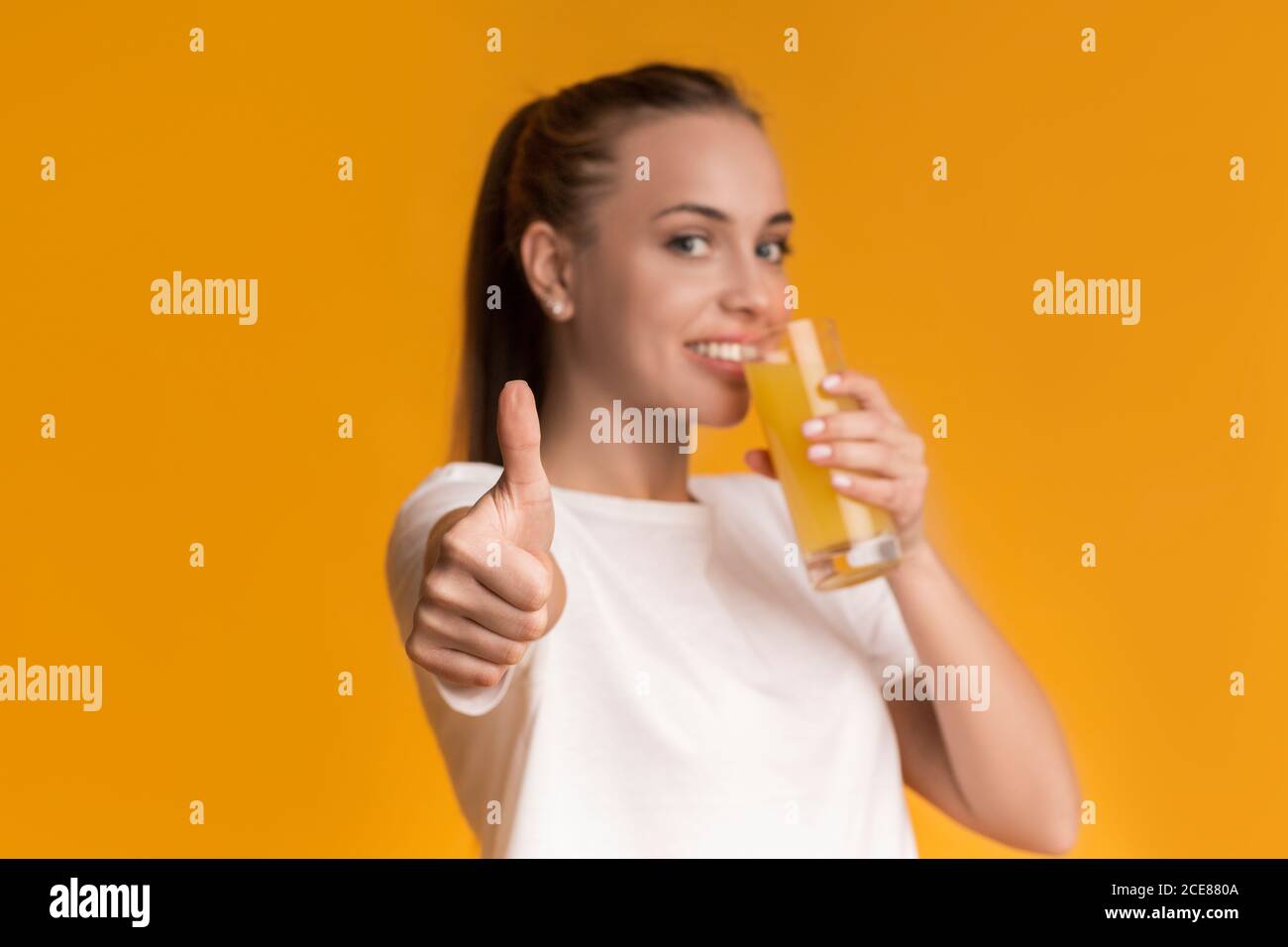 Young woman drinking healthy juice and showing thumb up gesture Stock ...