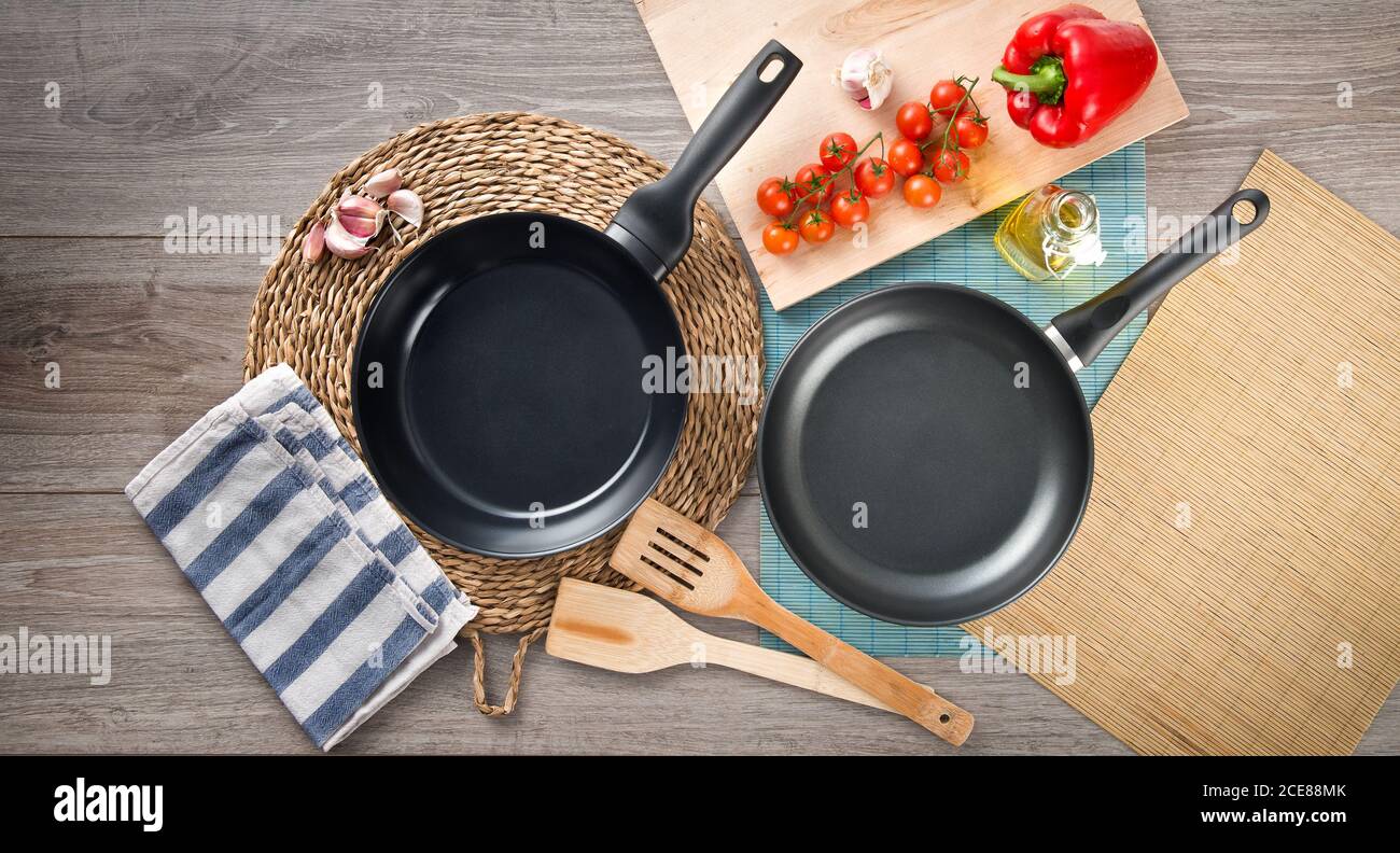 Modern frying pans above ground in studio Stock Photo - Alamy
