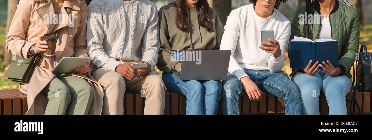 Cropped of students studying in park, using gadgets Stock Photo - Alamy