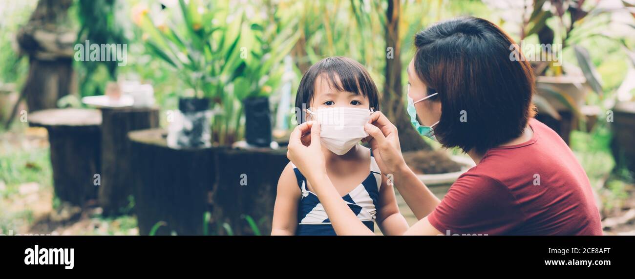 Mother take care daughter with face mask for protection disease flu or ...