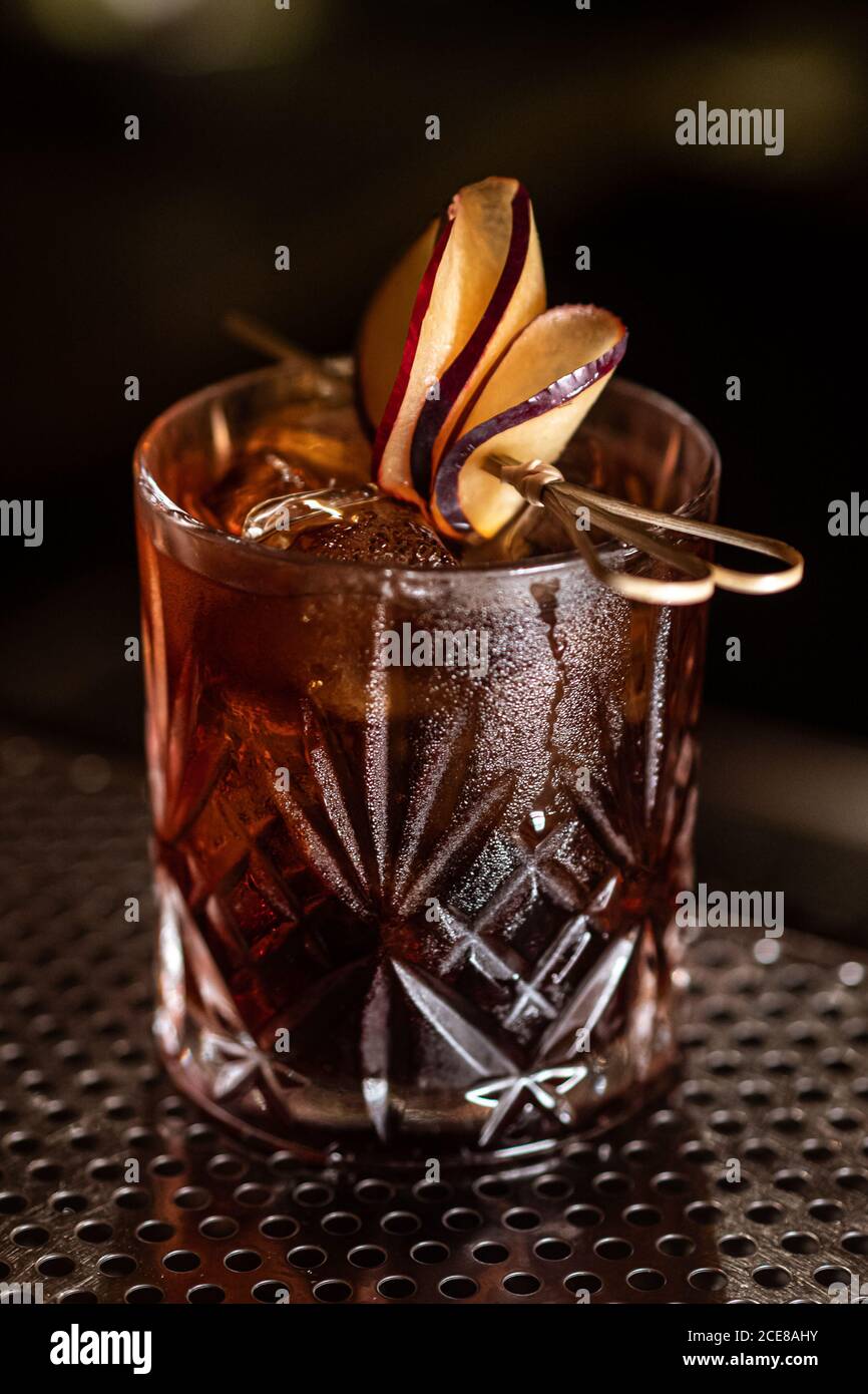 Shiny glass of alcohol cocktail with ice cubes garnished with fruit ...