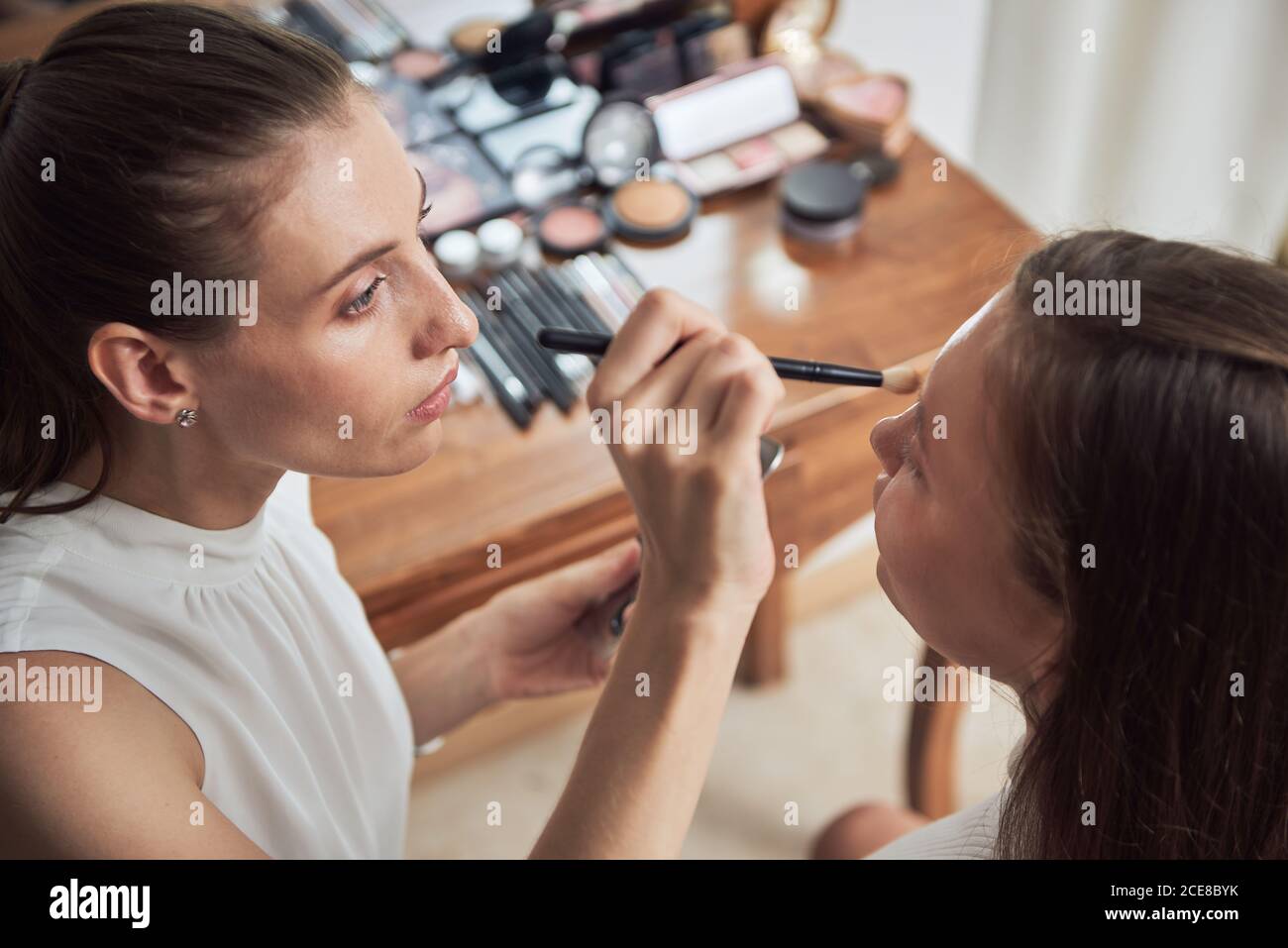 Crop focused makeup artist applying black eyeliner on young beautiful ...