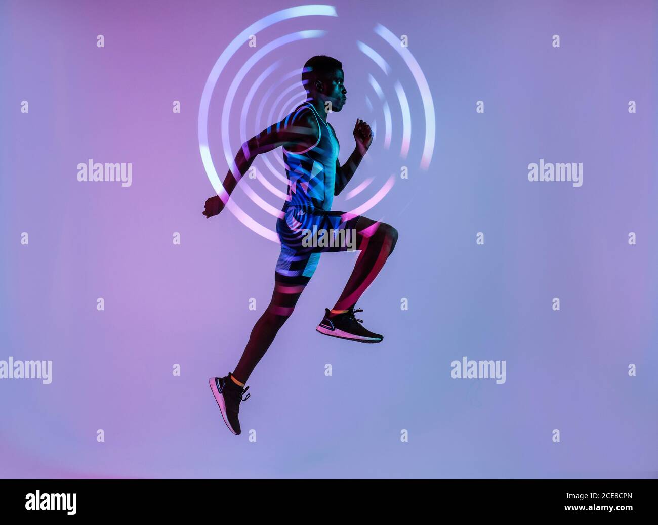 Side view of energetic young African American male sprinter jumping ...