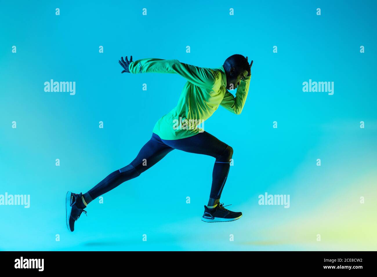 Full body side view of young African American male runner in colorful ...