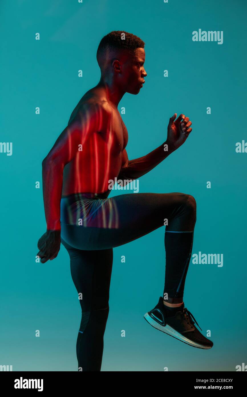 Full body side view of young African American male runner in colorful ...