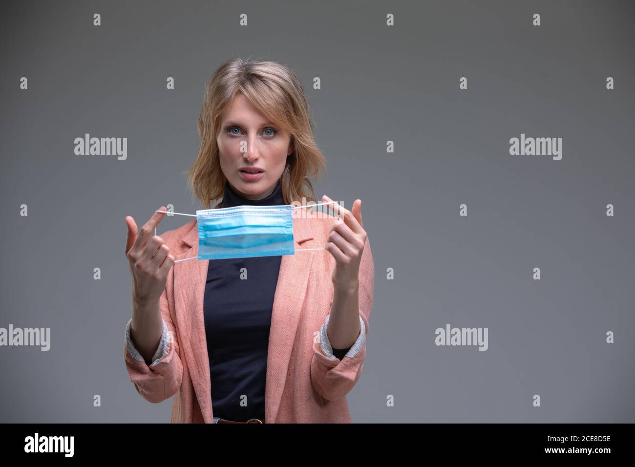 Blond woman hold her surgical mask Stock Photo - Alamy
