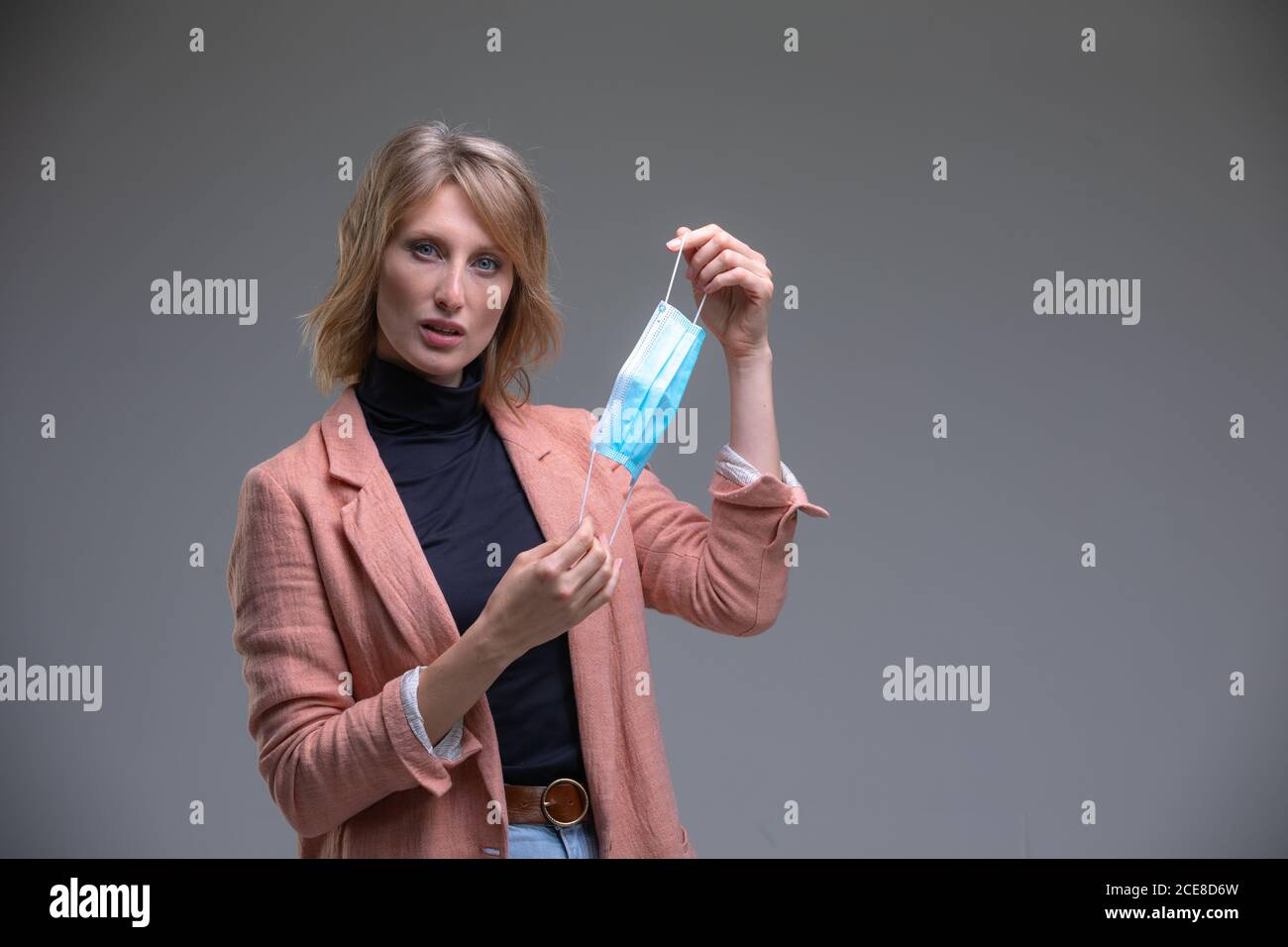 Blond woman hold her surgical mask Stock Photo - Alamy