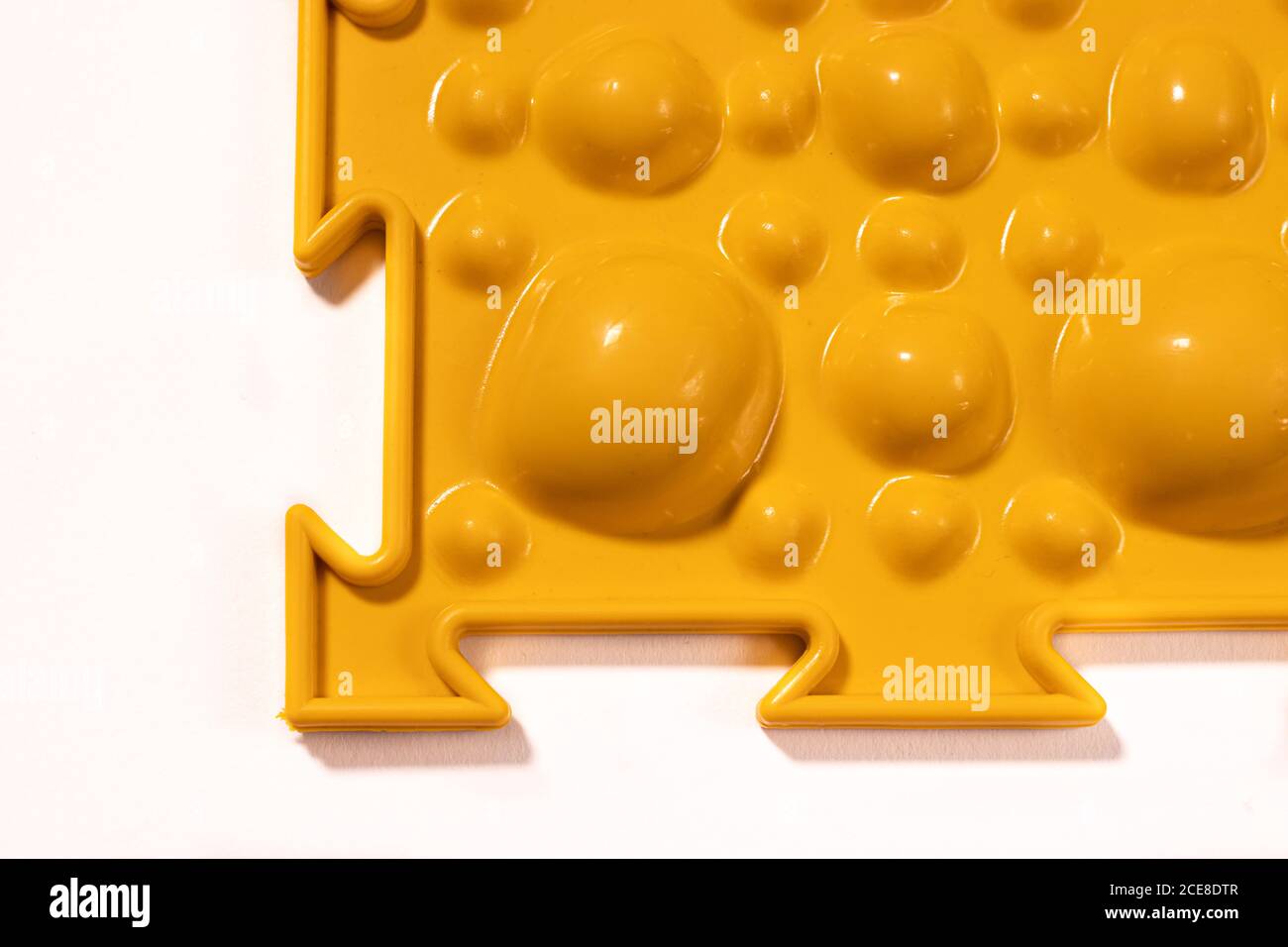 Yellow orthopedic mat in the form of small stones on a white background ...