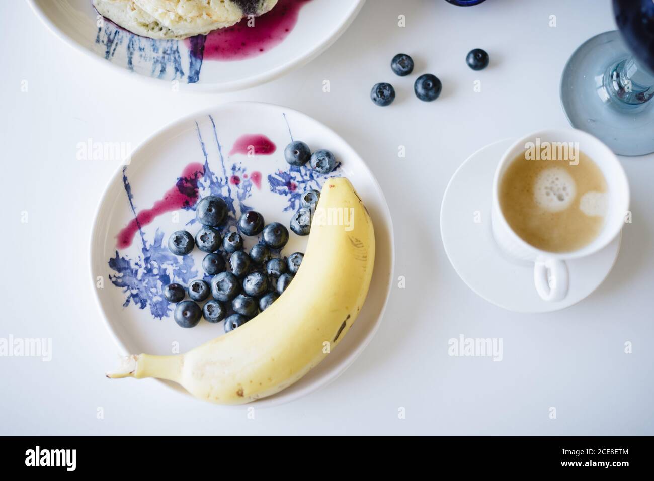 Top view of fresh blueberries and a banana served with cup of coffee on ...