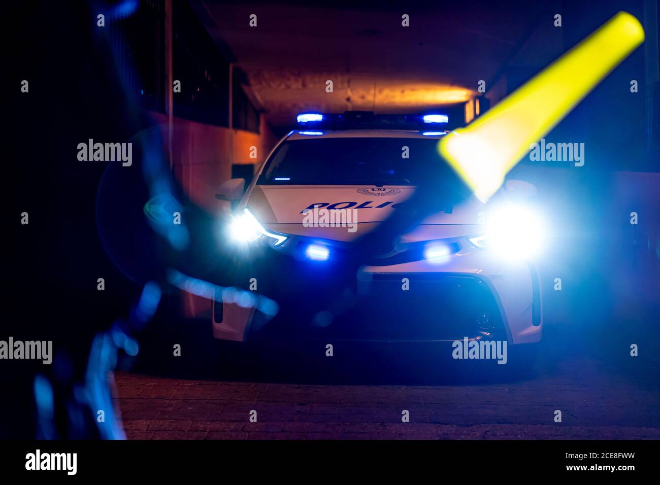 Back view of crop police officer standing with illuminated traffic wand ...