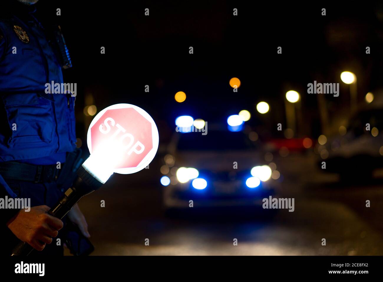 Side view of crop policeman wearing uniform with illuminated stop sign ...