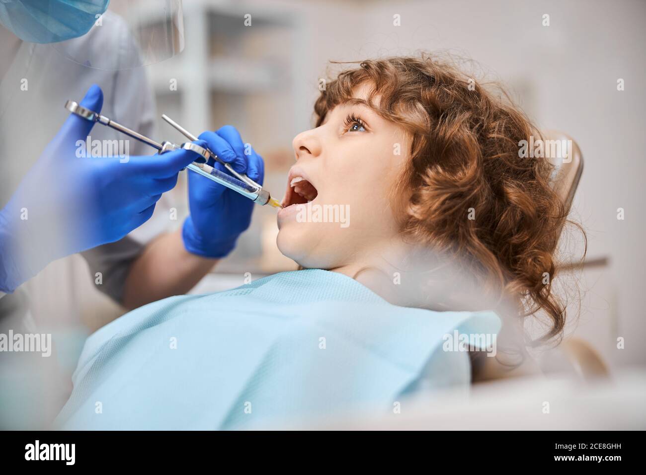Boy in dental chair getting anesthesia in clinic Stock Photo - Alamy