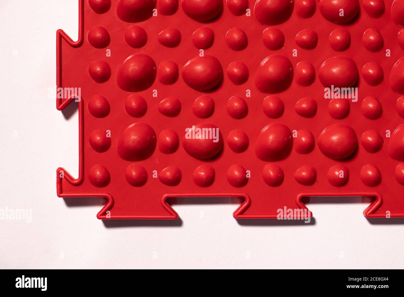 Red orthopedic mat in the form of small stones on a white background ...