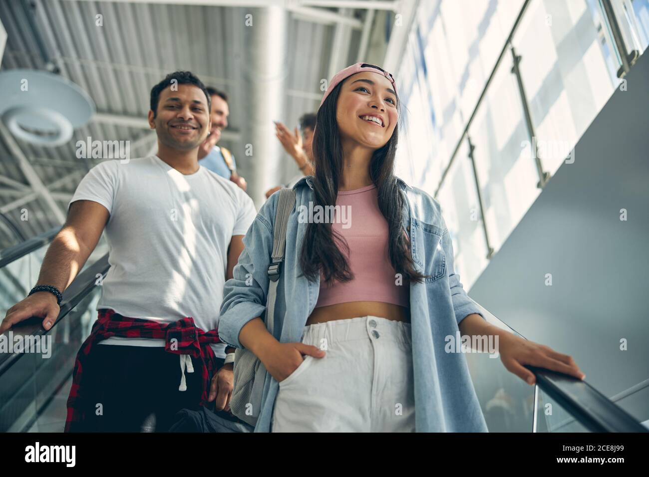Happy smiling group standing on moving staircase Stock Photo - Alamy