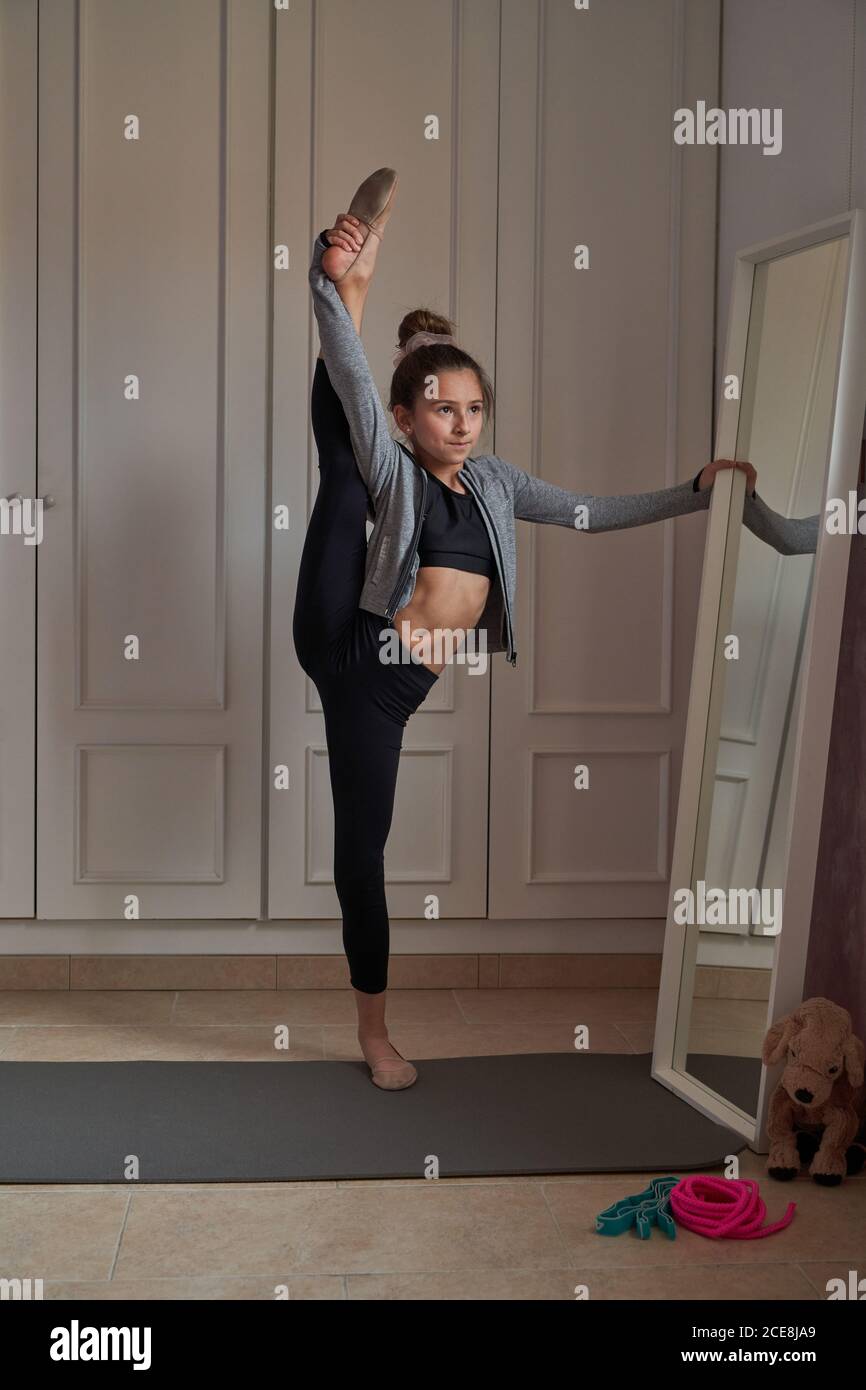Flexible teen girl standing with leg raised high in splits training in ...