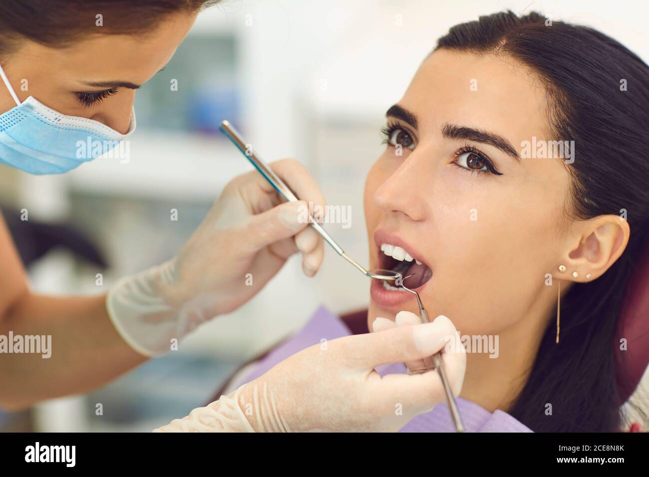 Dentist examining woman patients tooth in dental clinic Stock Photo - Alamy