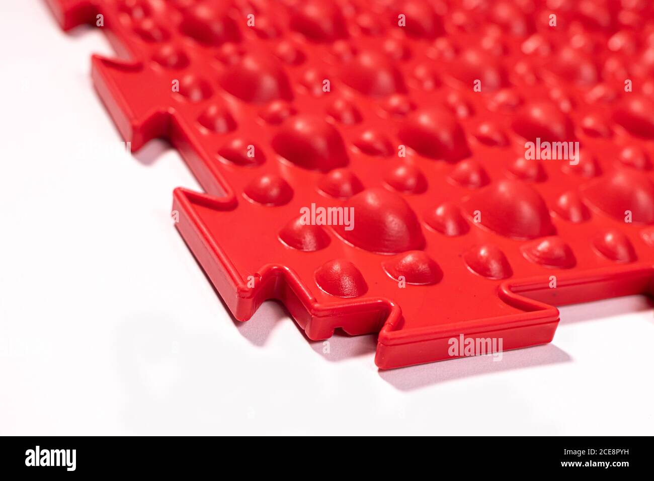 Red orthopedic mat in the form of small stones on a white background ...