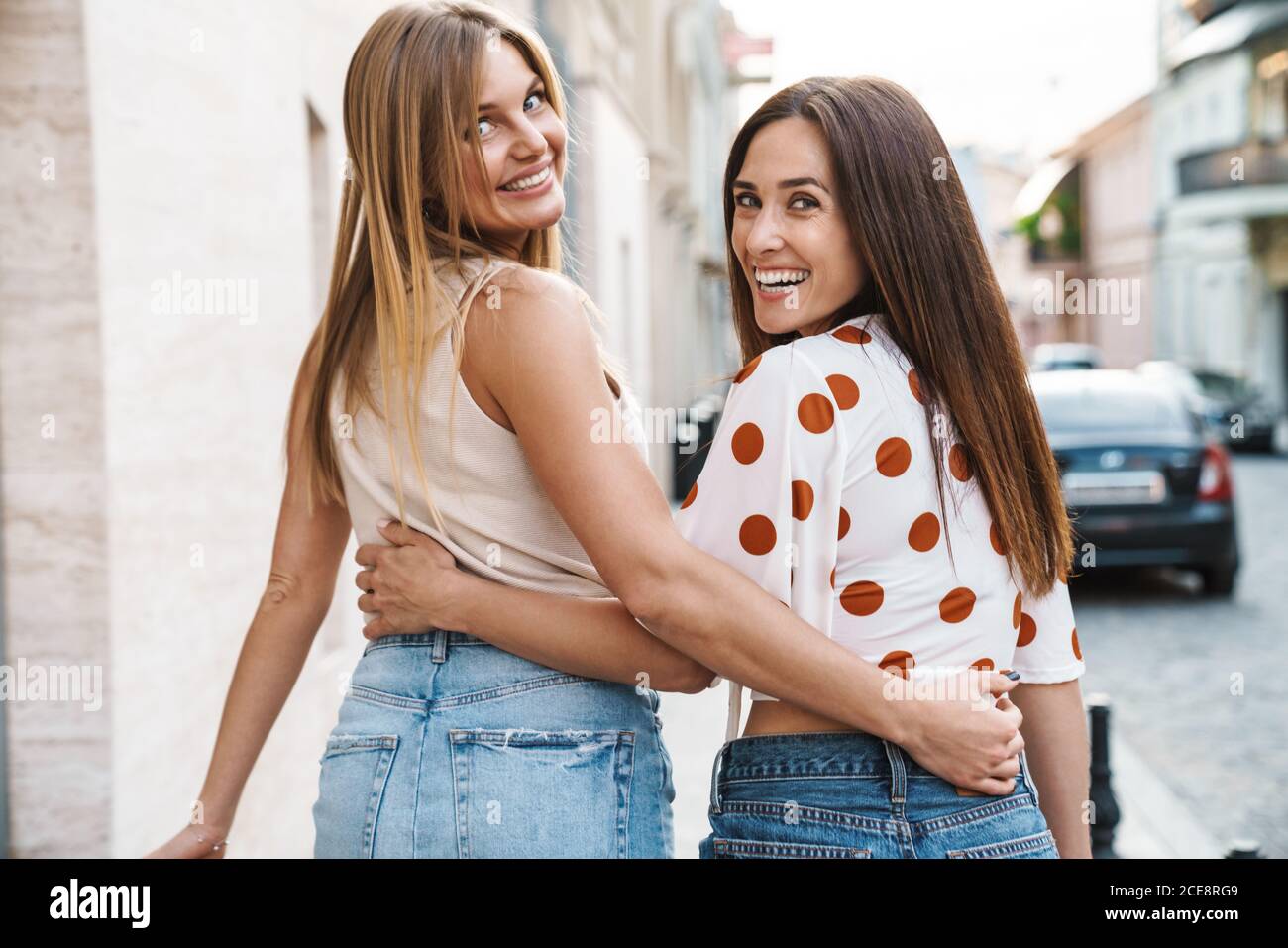 Image of cheerful adult two women hugging and laughing while walking on ...