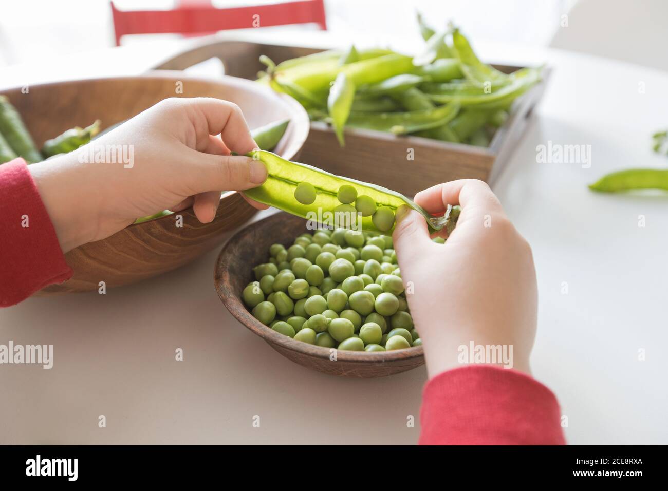 Crop little boy peeling pea pods in kitchen Stock Photo - Alamy
