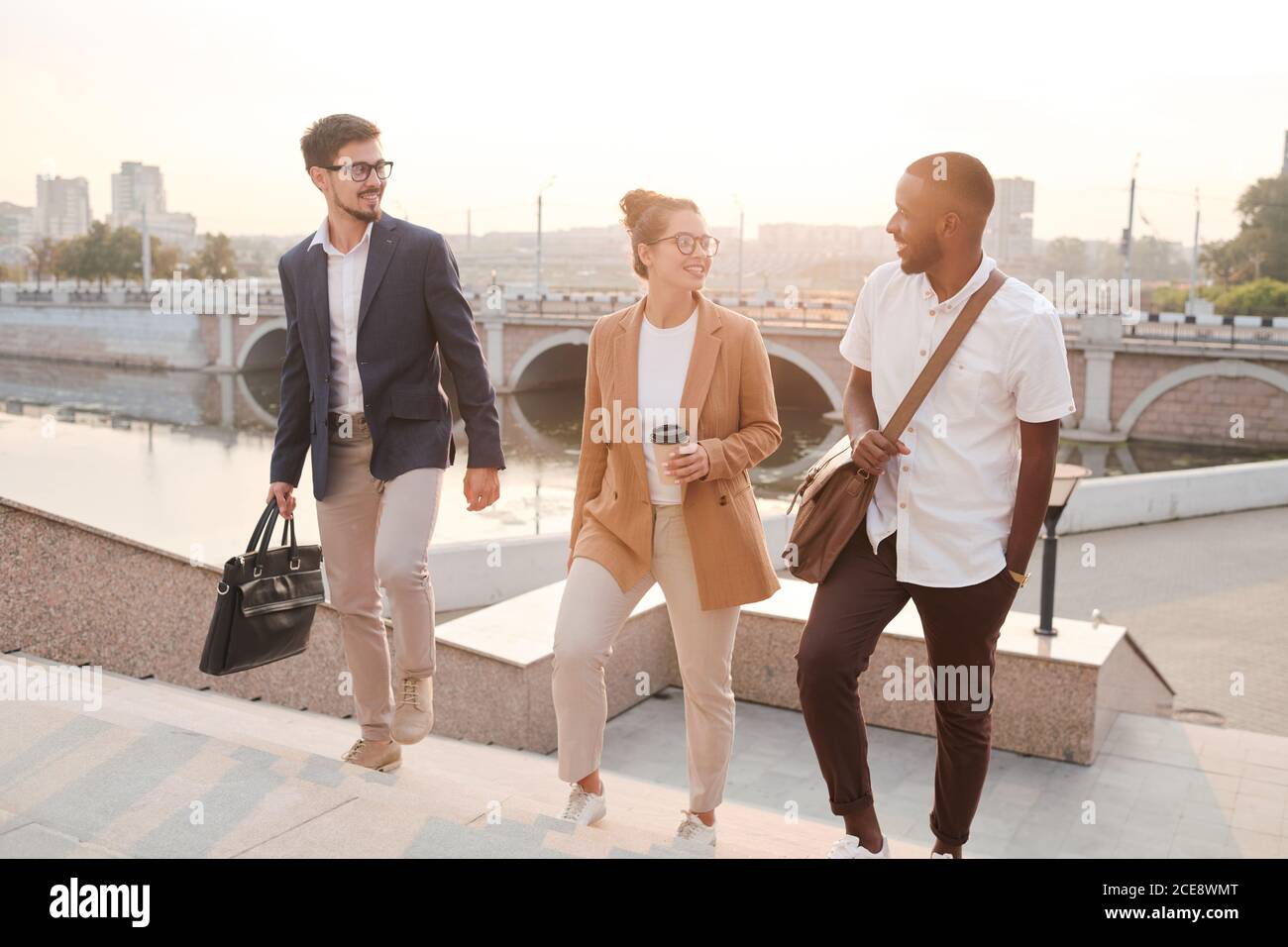 Cheerful young multi-ethnic students moving up university staircase and ...