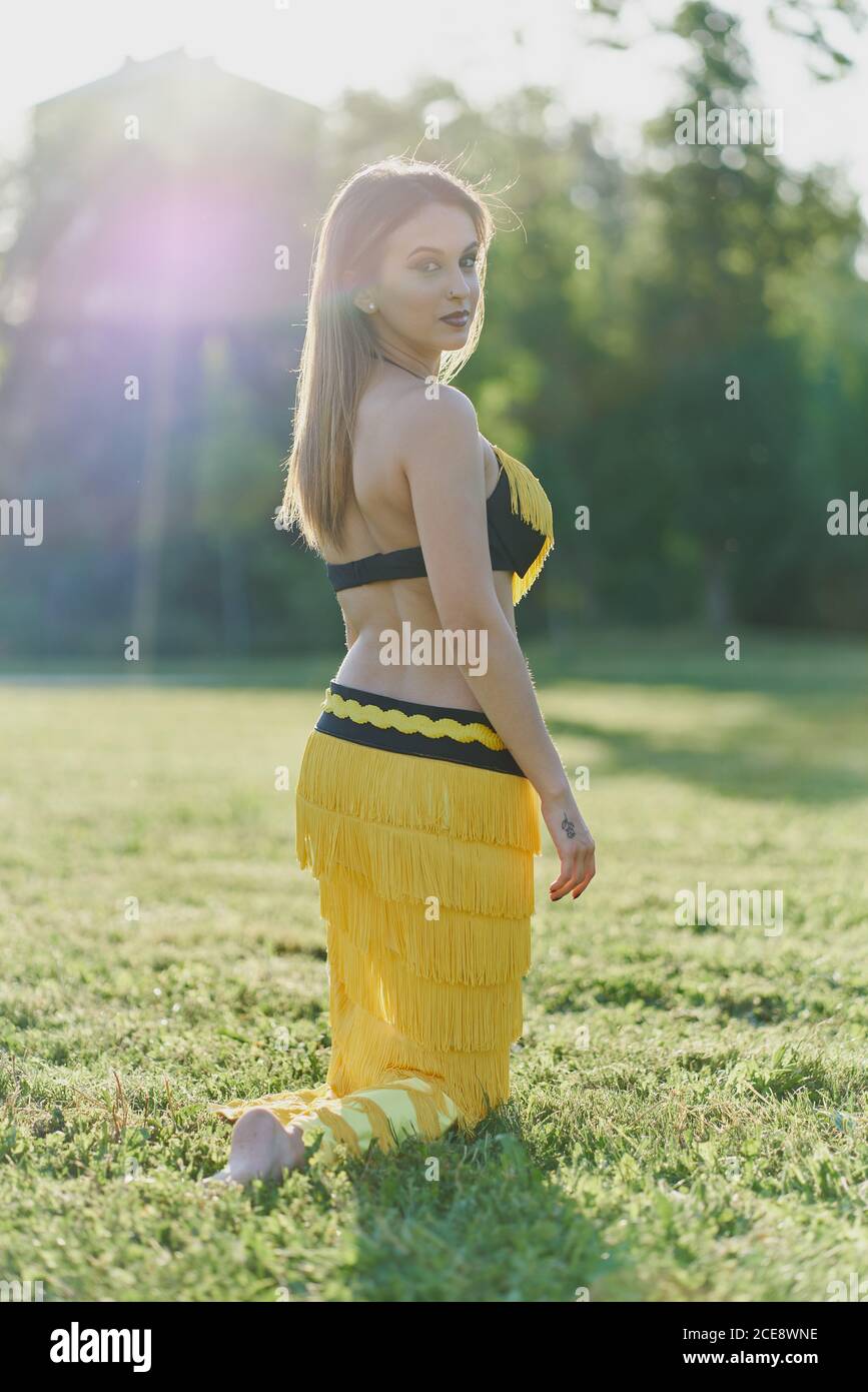 Back view of female belly dancer performing oriental dance while ...