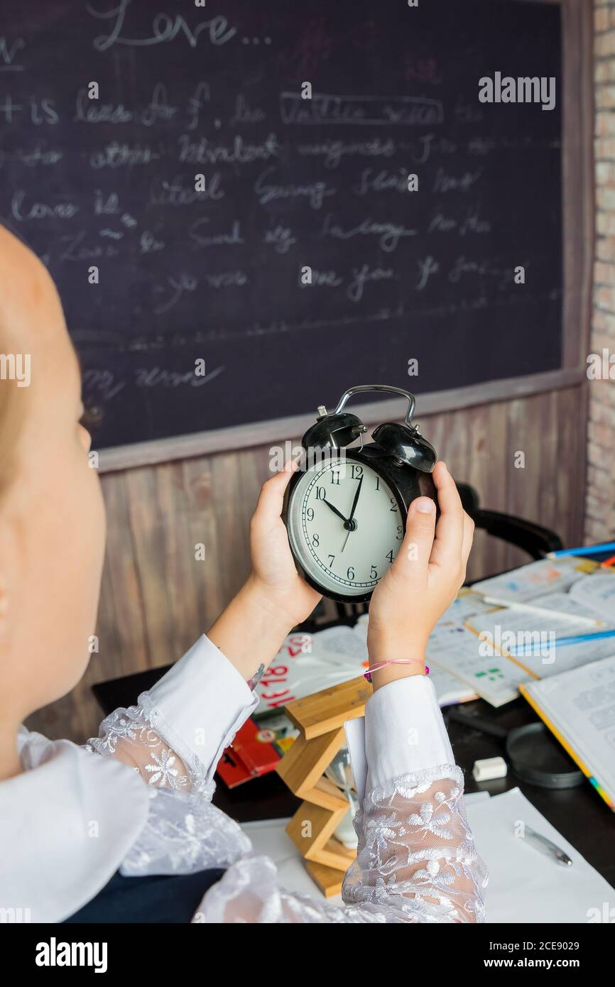 Child, schoolgirl hold black alarm clock. Always on time. Controlling ...