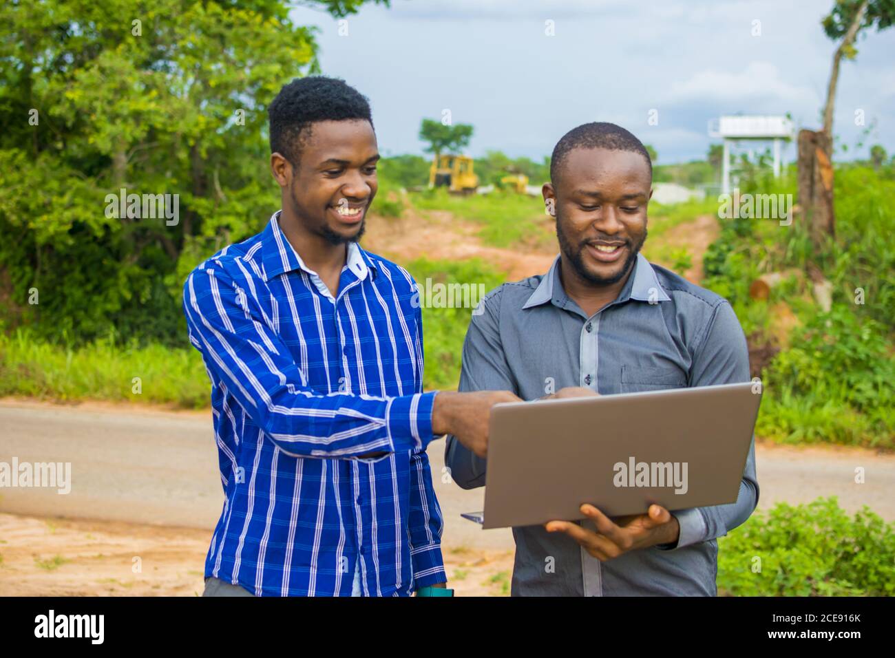African men discussing business plans with a notebook standing in a ...