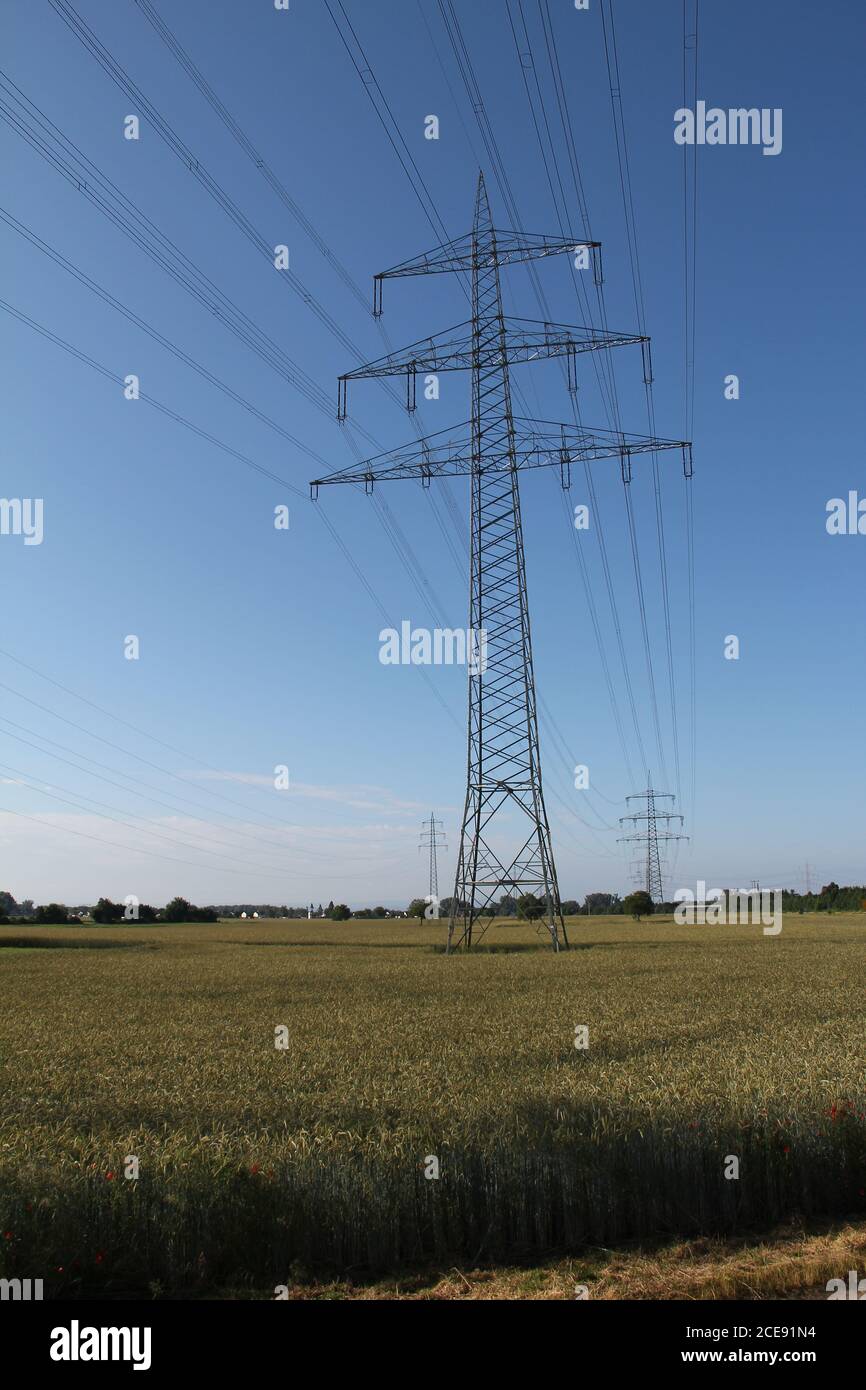 Vertical shot of power transmission lines on a field with a clear sky ...