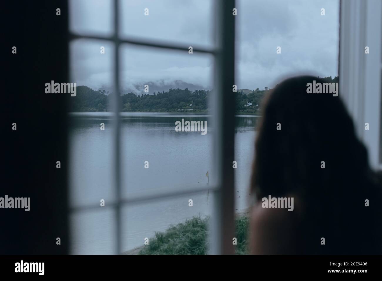 Woman looking through window of room Stock Photo - Alamy