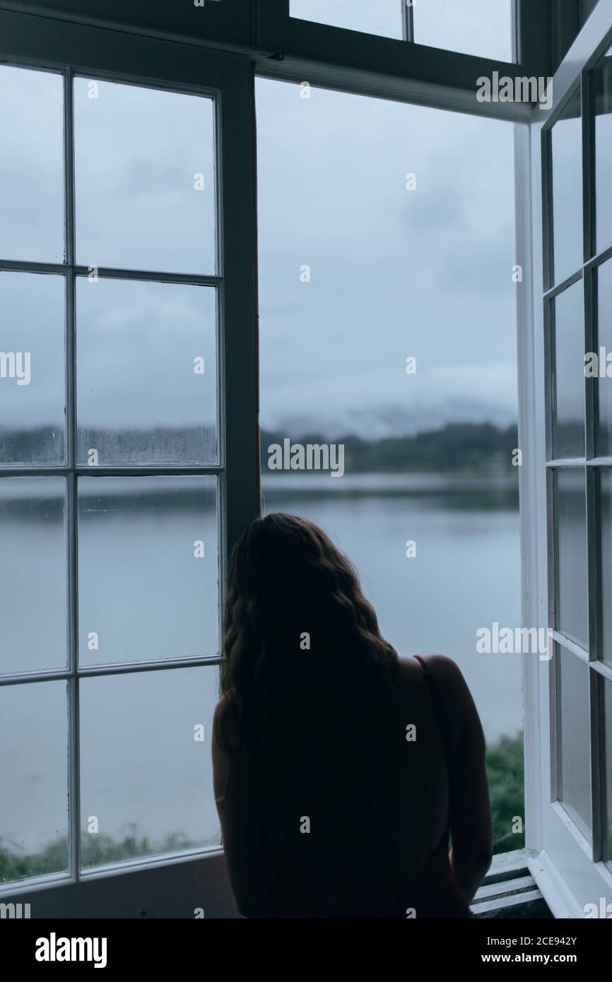 Woman looking through window of room Stock Photo - Alamy