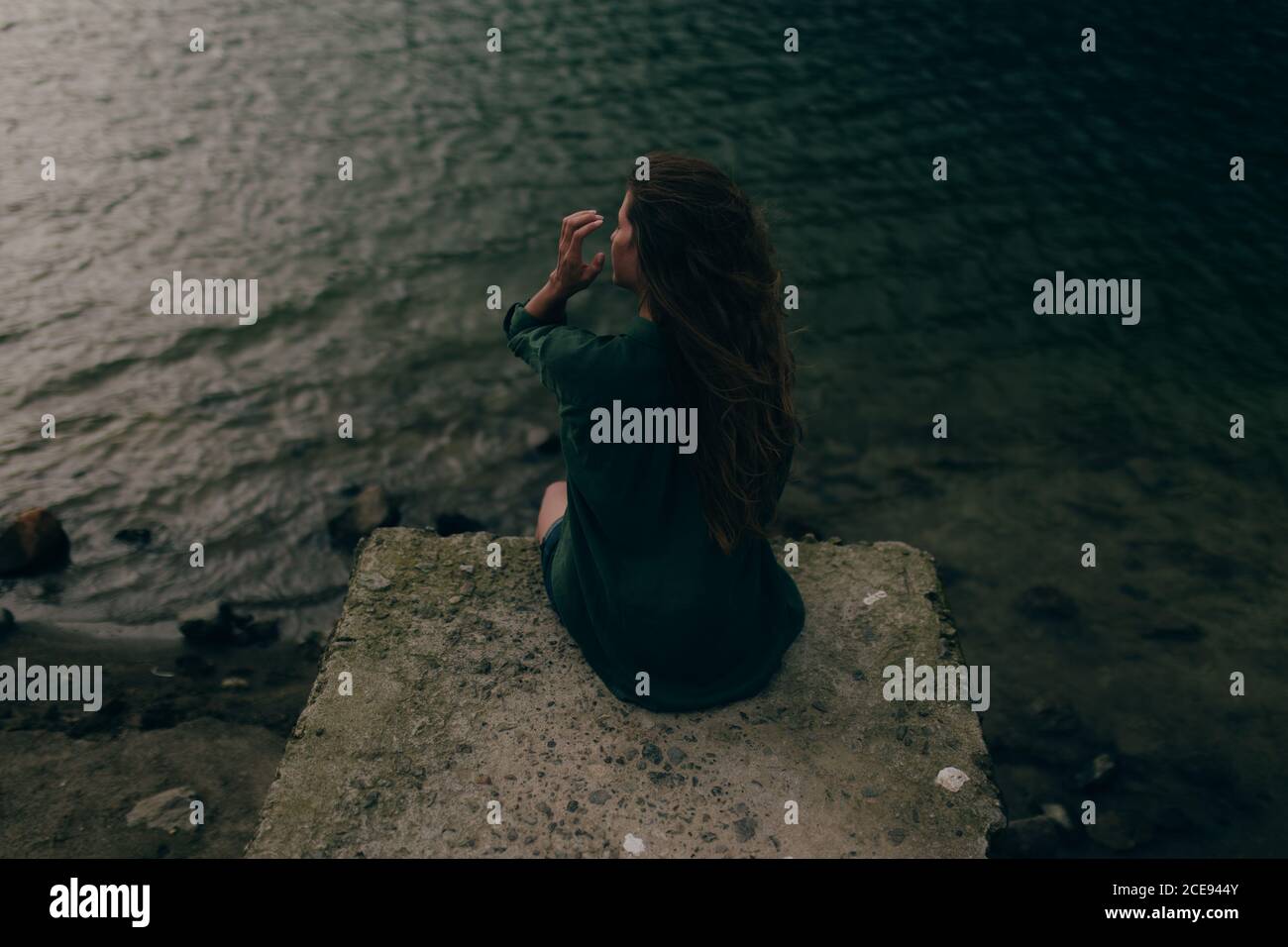 Young Woman sitting on cliff near lake Stock Photo - Alamy