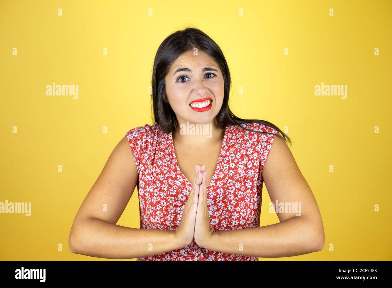 Young beautiful woman over isolated yellow background begging and ...