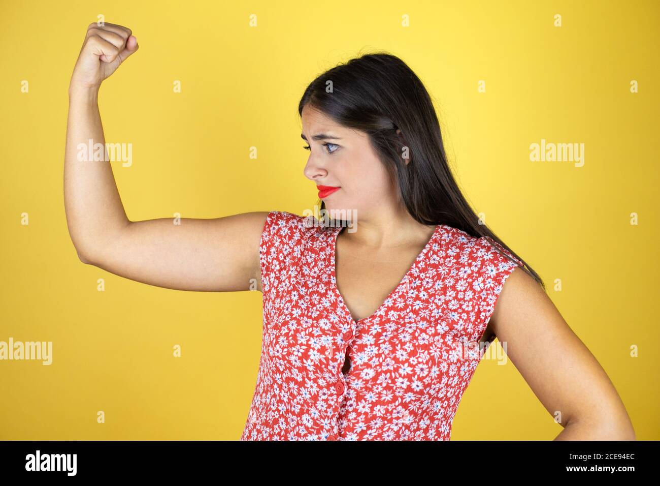 Young beautiful woman over isolated yellow background showing arms ...