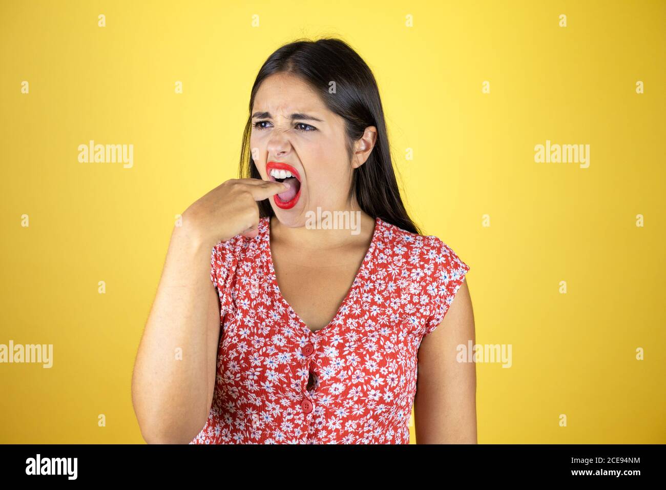 Young beautiful woman over isolated yellow background disgusted with ...