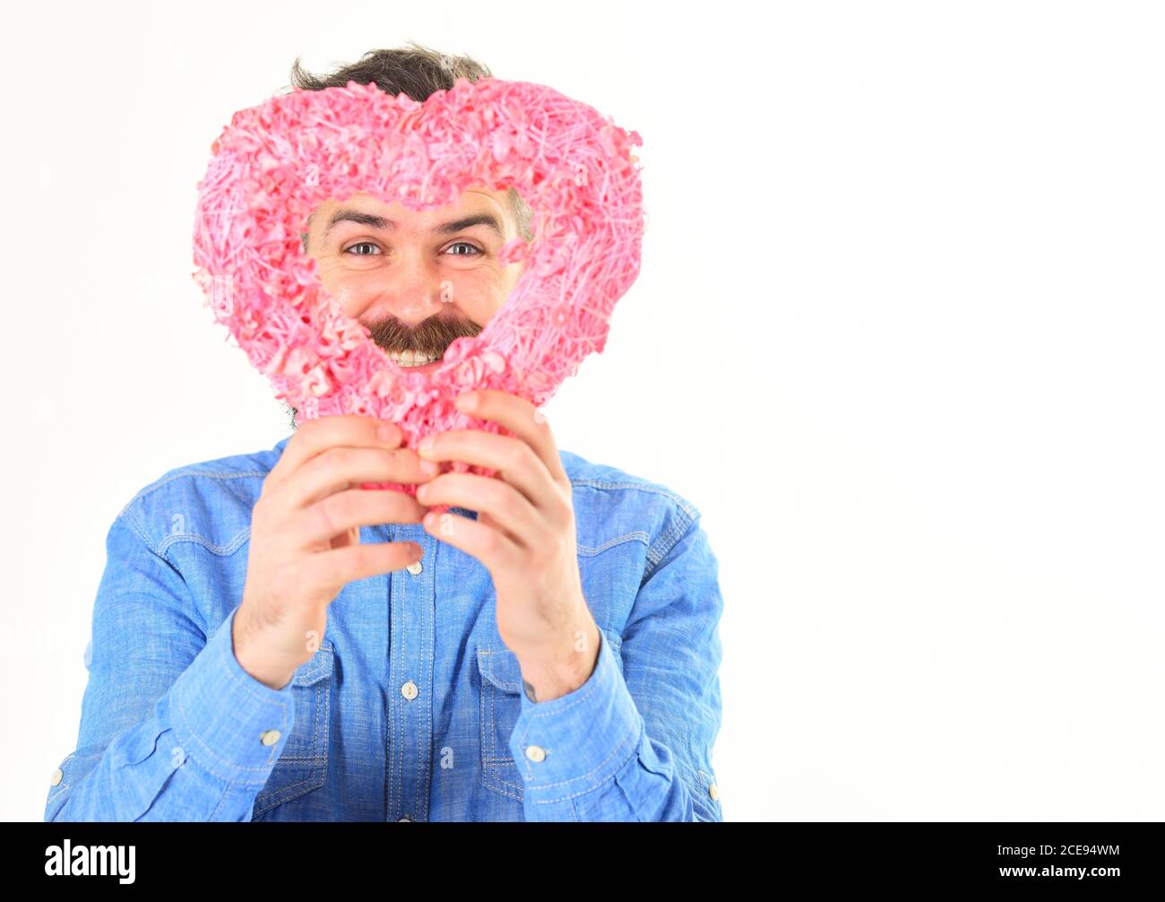 Man with happy face looks through pink heart. Man with mustache holds ...