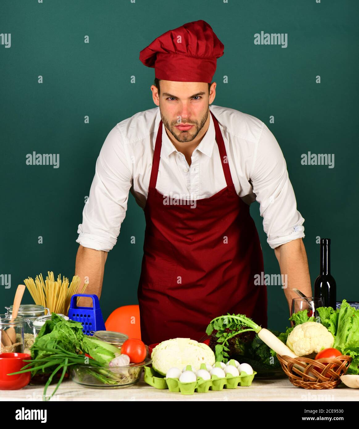 Cook works in kitchen near table with vegetables and tools. Man in ...