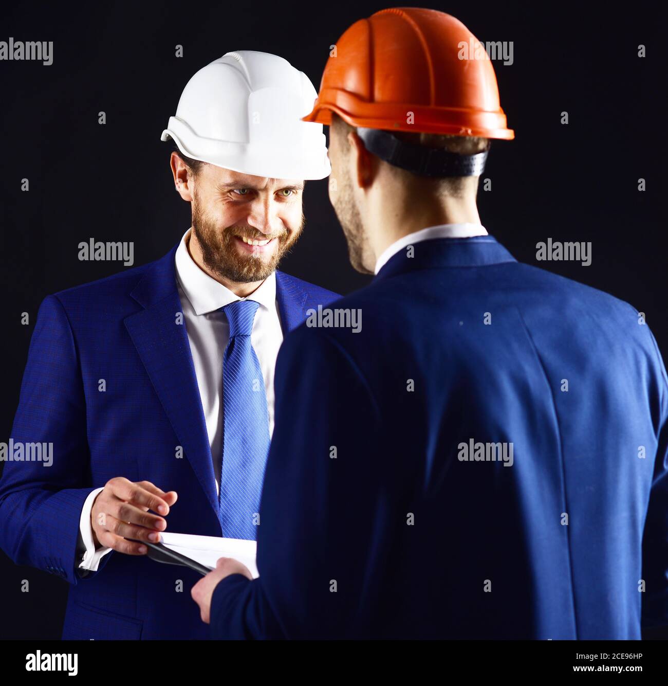 Boss in helmet gives instructions to employee. Engineers with smiling ...