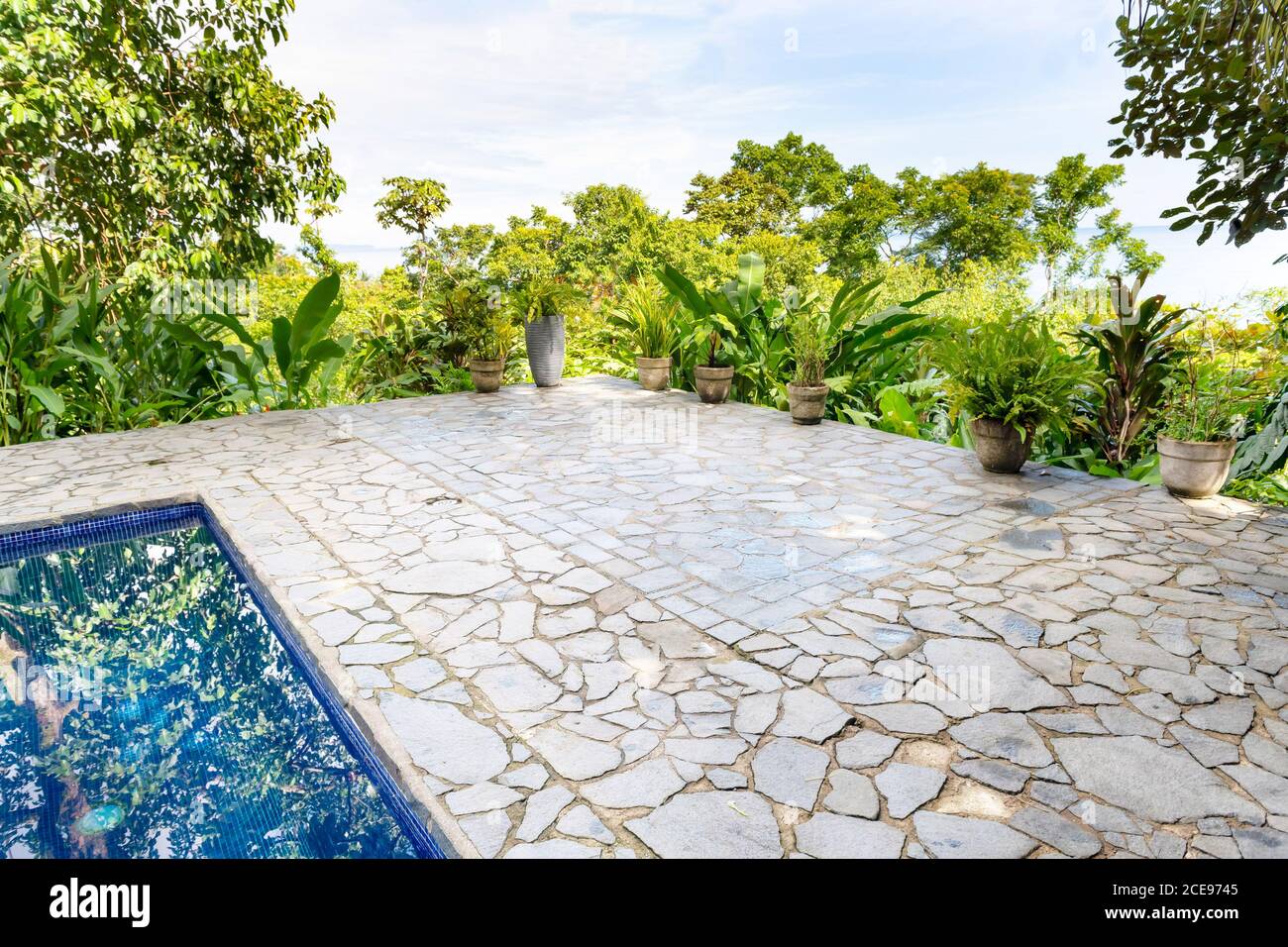 An open and empty terrace of beige natural stone next to a blue pool ...