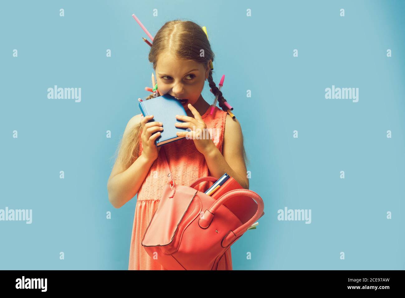 Back to school and childhood concept. Girl with pink bag bites blue ...